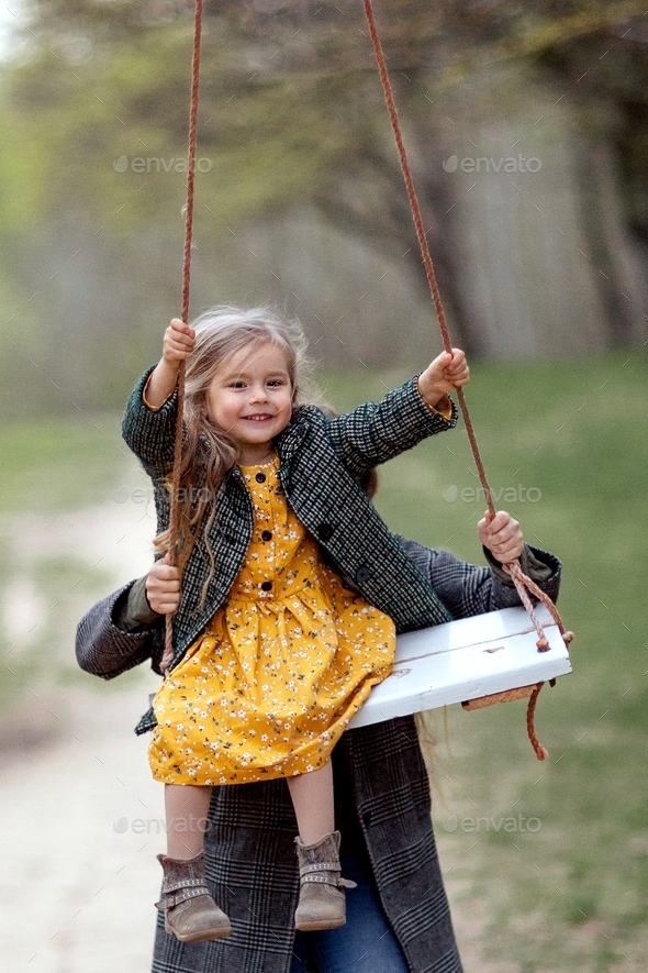 Spring. little girl riding on a swing Stock Photo by katyatsiganok