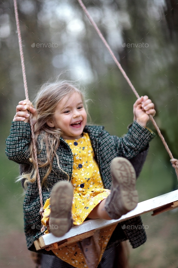 Spring. little girl riding on a swing Stock Photo by katyatsiganok