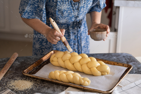 The girl makes challah bread in the kitchen, smears butter with a brush ...