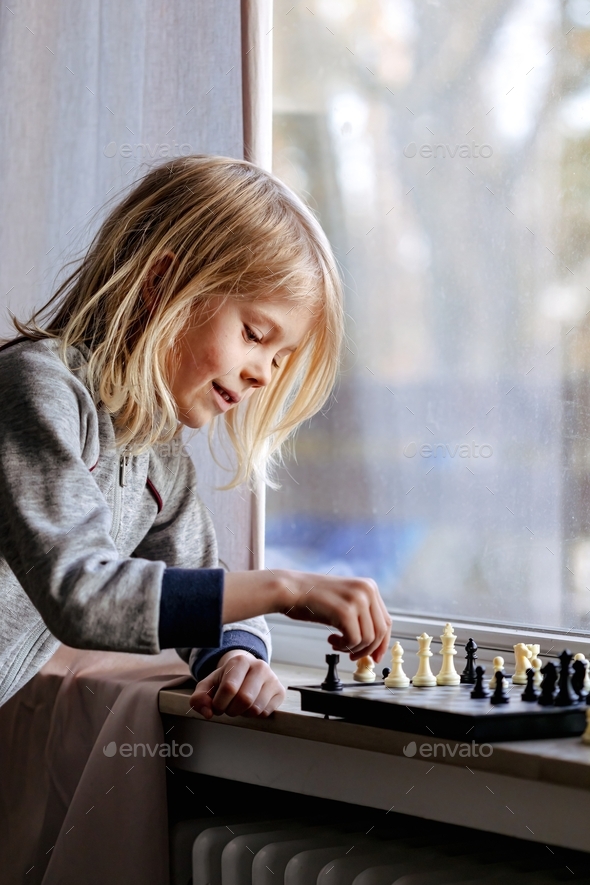 The boy is learning to play chess standing by the window Stock Photo by ...