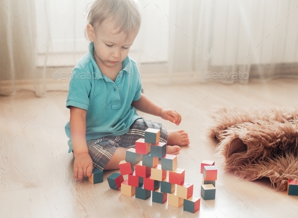 Happy child building tower with colored cubes Stock Photo by OlgaKhorkova