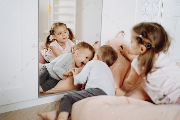 Cute children having fun making funny faces in front of mirror at home ...