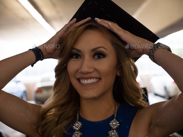 Young woman with graduation cap on head smiling looking at camera ...