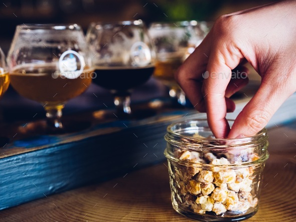 Hand grabbing snack from cup with beer flight tasters at brewery sample ...
