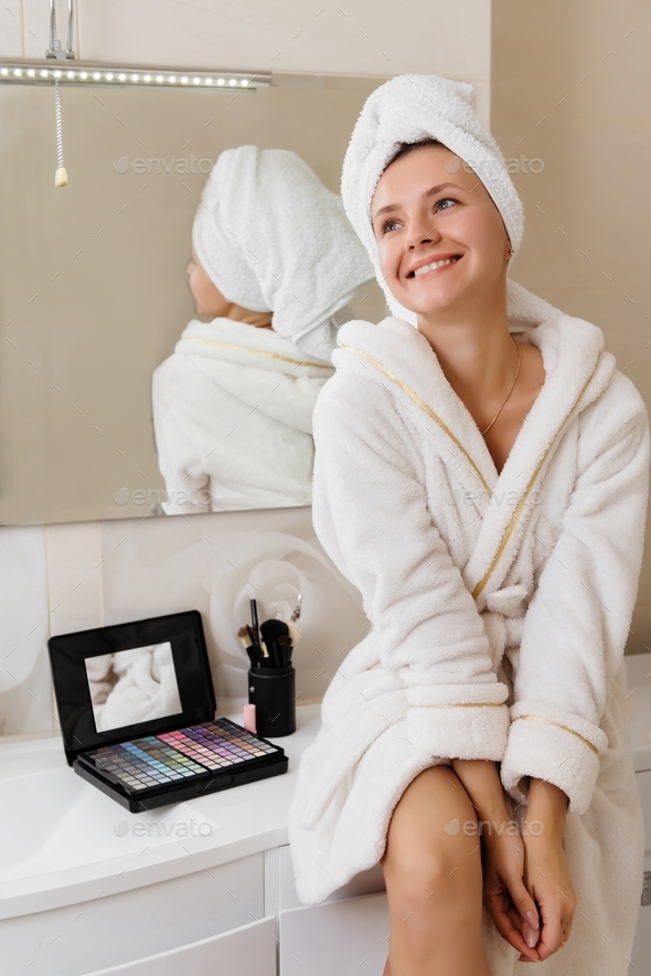 Woman doing herself makeup at home after taking shower. Self skin care ...