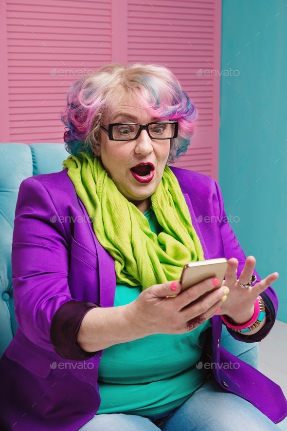 Stylish senior woman using smart golden phone and express surprise ...