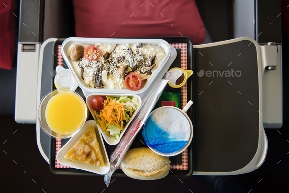 Food served on board of airplane on the table. Fresh meal with salad ...
