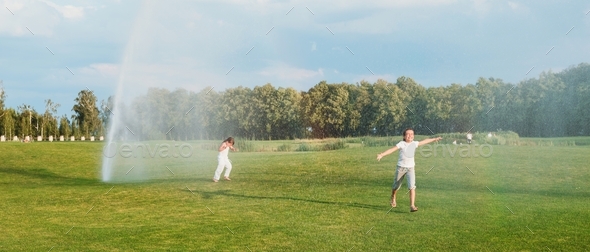 Happy children running under sprinkler water in park Stock Photo by ...