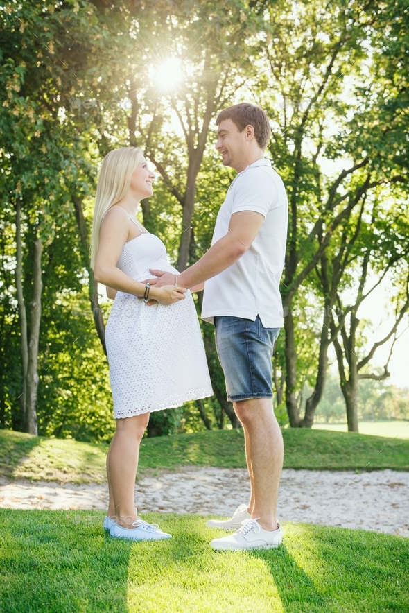 Happy husband touches belly of his pregnant wife. Sun shine thought the ...