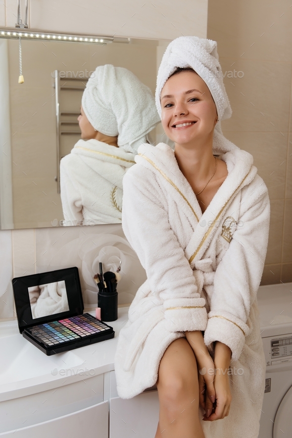 Woman doing herself makeup at home after taking shower. Self skin care ...