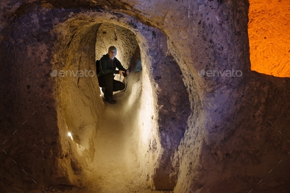 man with lights exploring caves in Derinkuyu ancient multi-level ...