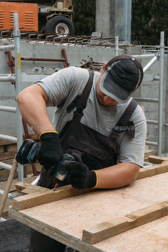 Man using screwdriver while working with wooden materials on ...