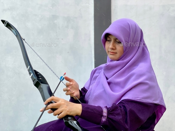 Hijab young woman sitting and preparing archery set Stock Photo by ...