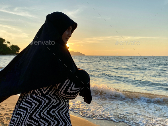 Lady wearing black hijab at sunset on the beach Stock Photo by arief ...
