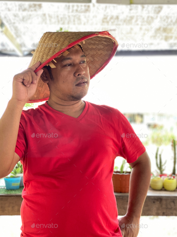 Young asian man in red shirt wearing traditional hat made of woven ...