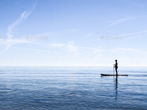 Photo of a man using a stand up board in the ocean Stock Photo by lindaze