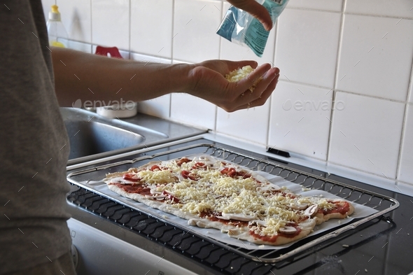 Photo of a man putting cheese on a pizza when cooking Stock Photo by ...