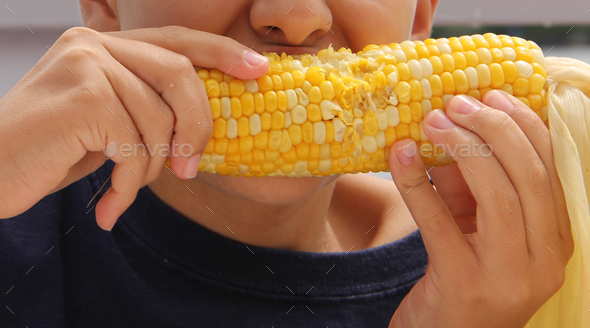 June 11th is Corn on a Cob day. Boy eating and taking a big bite of ...