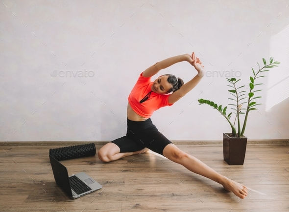 young sports girl goes in for sports at home with a laptop, an athlete ...