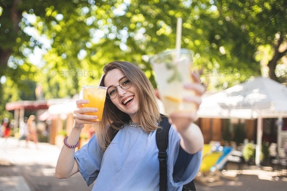Beautiful and smiling girl drinks lemonade and walks the streets of the ...