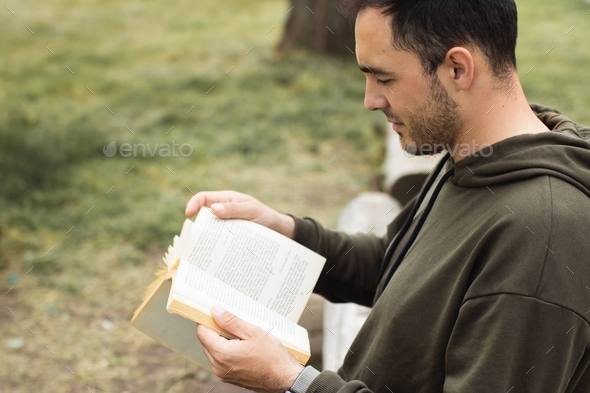 Handsome guy is reading a book in the park. Reading books. The student ...
