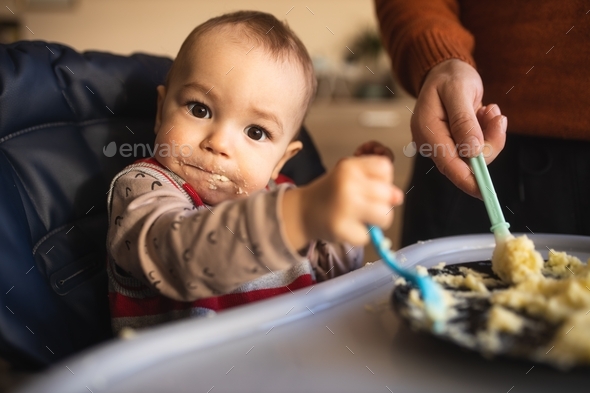 Little boy is learning to eat. Complementary feeding of the child. The ...