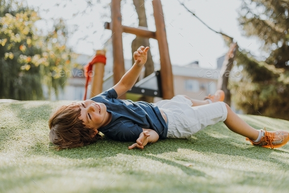 happy tired after training child lies on the green grass and rests ...