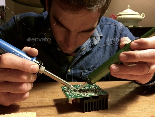 Man fixing electronic part with a welding iron at home Stock Photo by ...