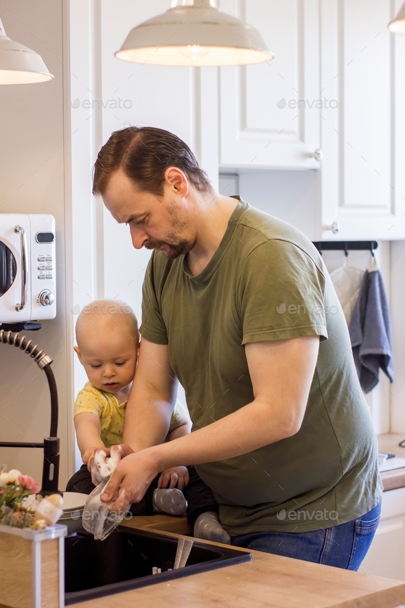 Father wash dishes on kitchen and little baby boy watching on it with ...