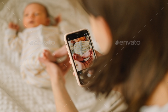 Mother taking photo of baby boy on mobile phone. Using technology Stock ...