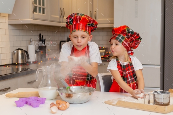 children in chef costumes prepare dough from flour, milk, eggs and ...