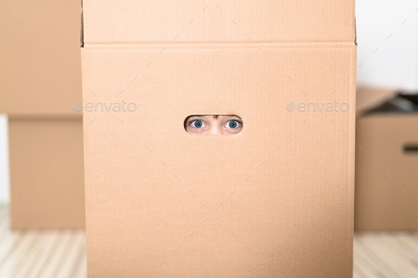 Boy hiding in inside a huge cardboard box. He is playing and peeking ...