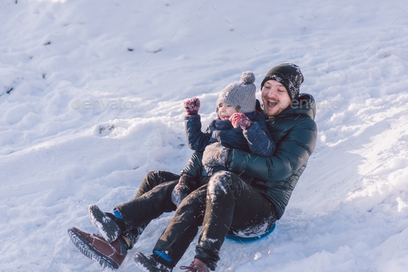 Happy dad and little boy playing with snow sled. Father and son ...
