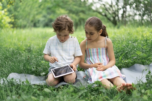 Children with a tablet outdoors. Children play games on the tablet ...