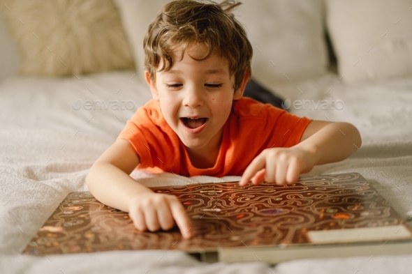 Kids read books. Little boy reading and plays with a book at home ...
