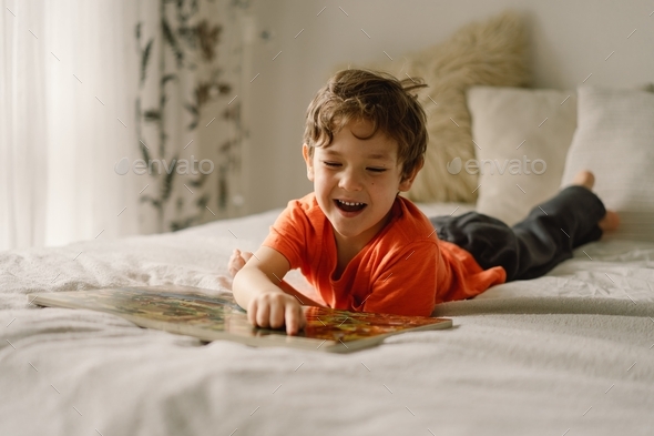 Kids read books. Little boy reading and plays with a book at home ...