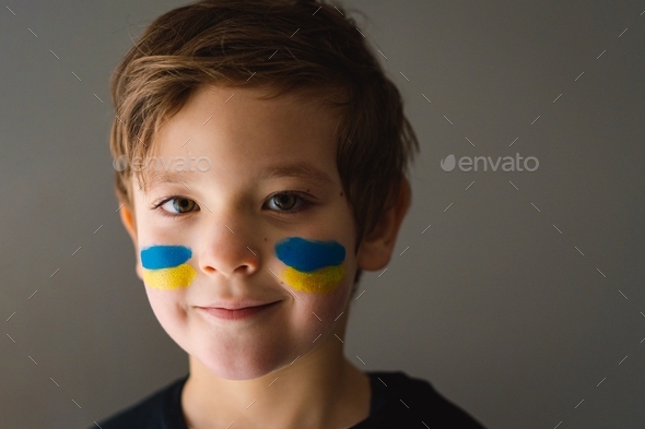 Portrait of a Ukrainian boy with a face painted with the colors of the ...