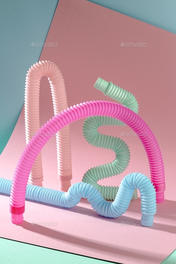 Pink antistress pop tube toy arch among curved shapes on pink and blue ...