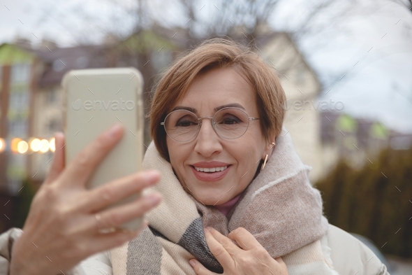 Beautiful baby boomer woman of middle age takes selfie on smartphone on ...