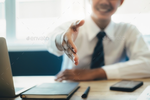 Smiling young Asian businessman executive extending his arm in a ...