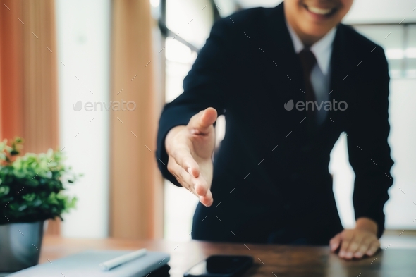 Smiling young Asian businessman executive extending his arm in a ...