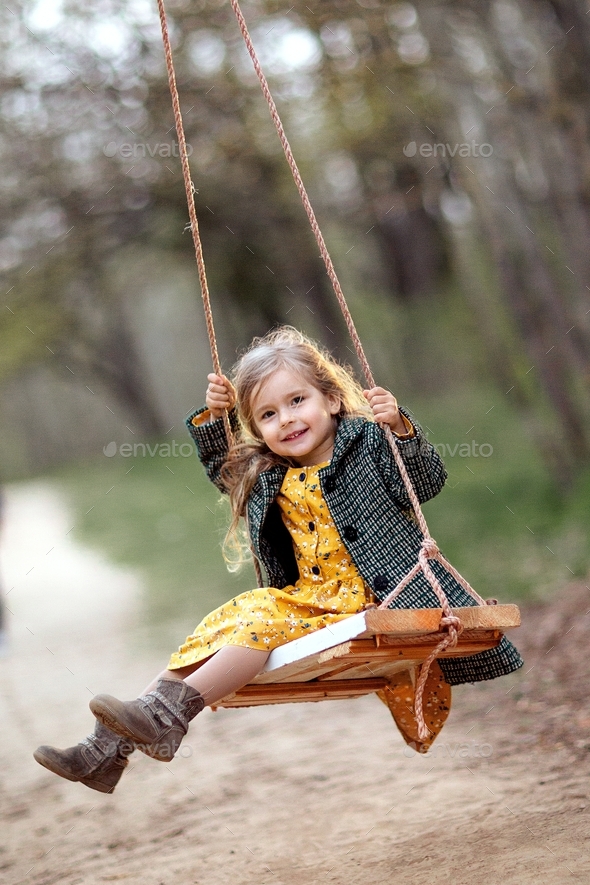 Spring. little girl riding on a swing Stock Photo by katyatsiganok