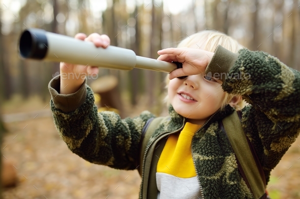 Little boy scout with spyglass during hiking in autumn forest. Child is ...
