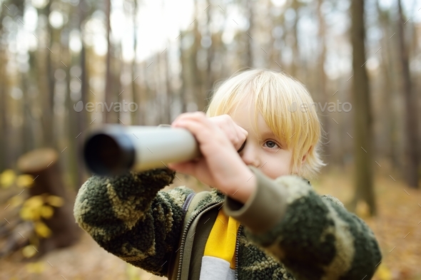Little boy scout with spyglass during hiking in autumn forest. Child is ...