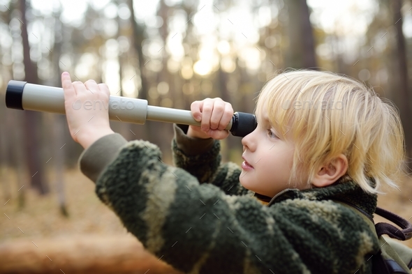 Little boy scout with spyglass during hiking in autumn forest. Child ...