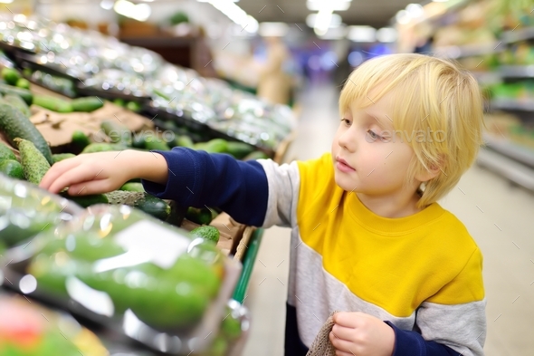 Cute little boy in a food store or a supermarket choosing fresh organic ...