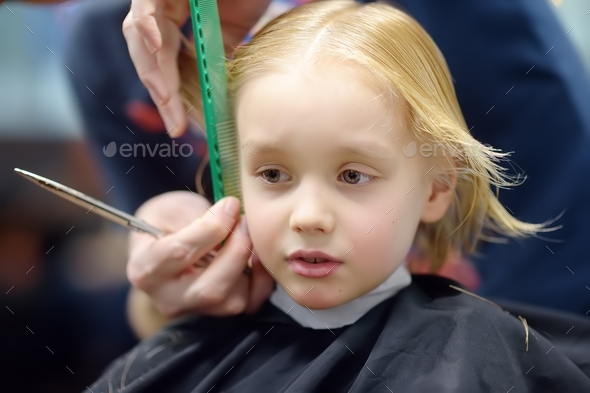 Preschooler boy getting haircut in barbershop. Children hairdresser ...