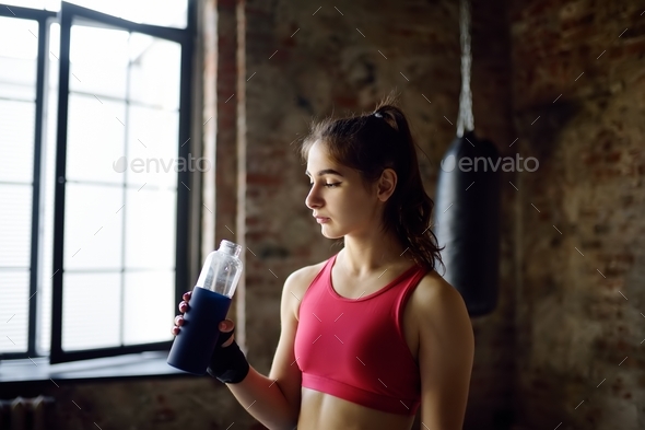 Portrait of young beautiful athlete in a boxing gym. A boxer girl ...