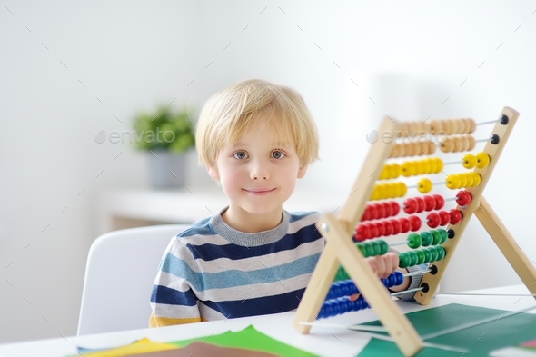 Elementary student boy doing homework at home. Child learning to count ...