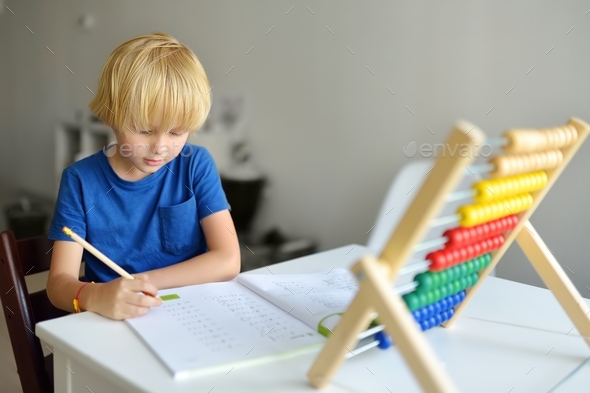 Elementary student boy doing homework at home. Child learning to count ...